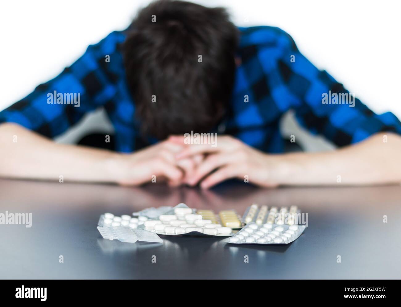 Depressed man taking drugs. Young man sitting on a table, drugs and ...