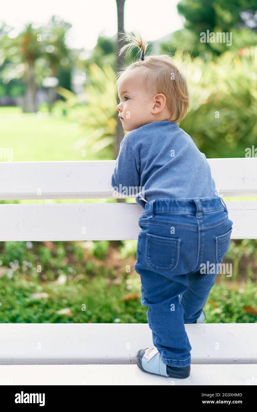 Little girl stands leaning on a white wooden fence in the park Stock ...