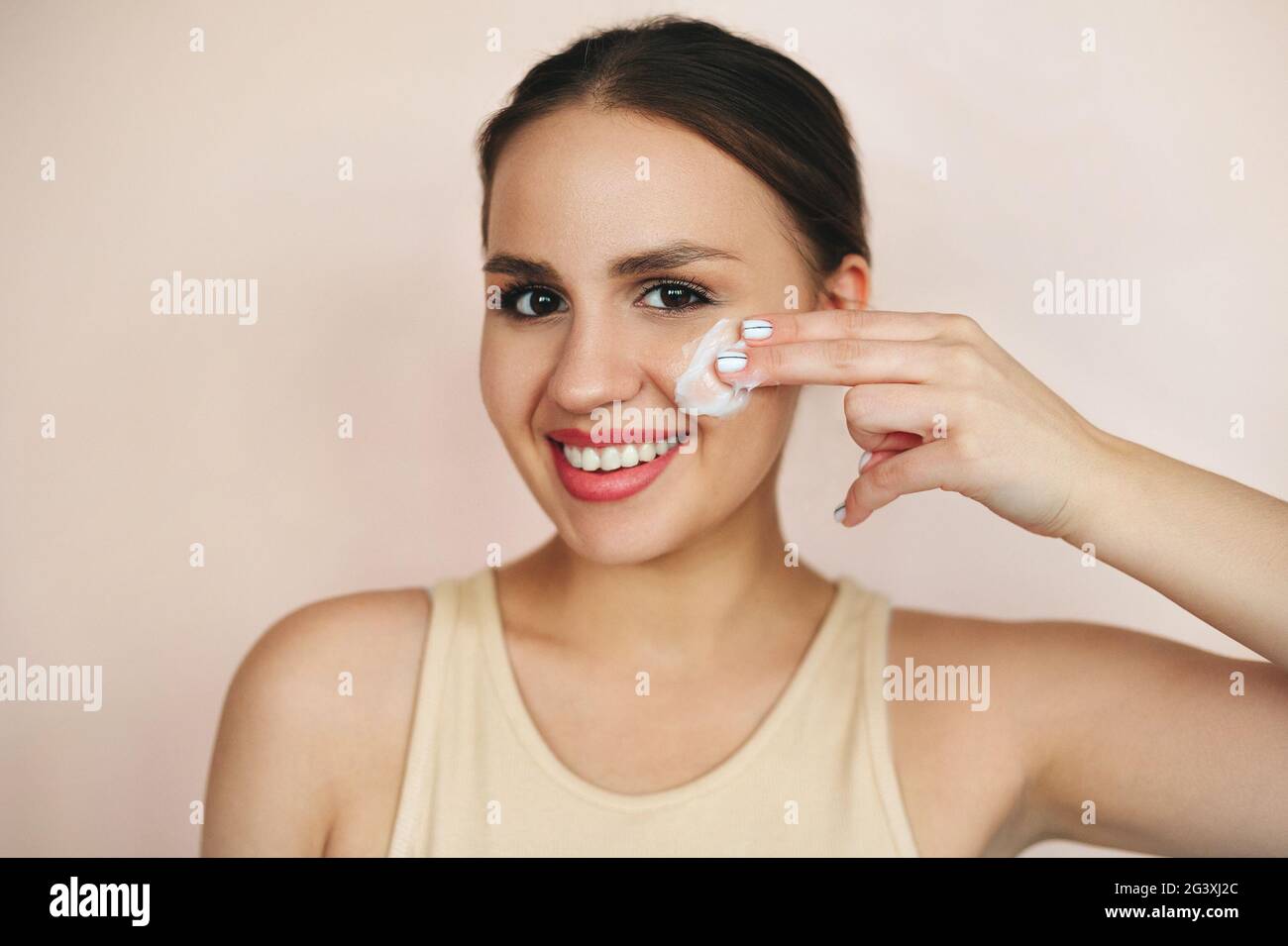 Young female smearing cream on face Stock Photo - Alamy