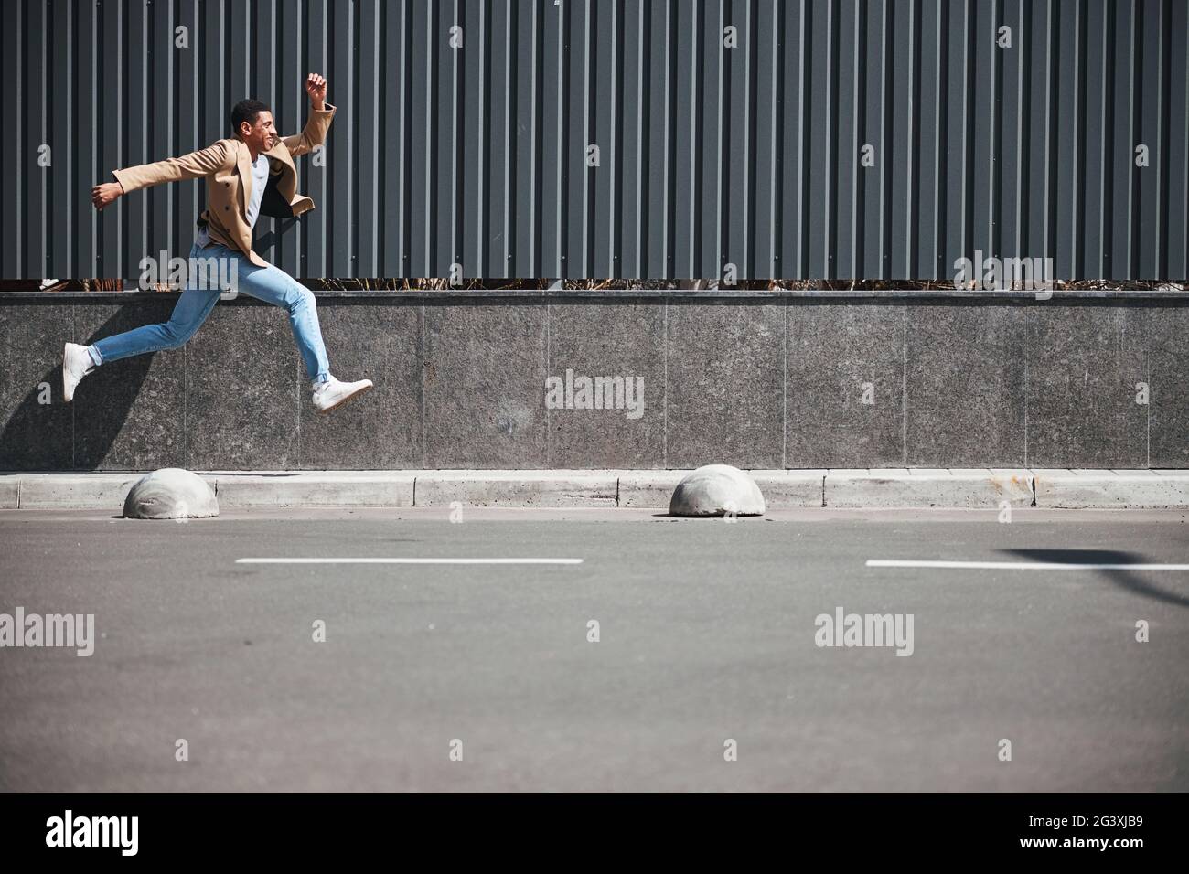 Happy dark-skinned male running home from office Stock Photo - Alamy