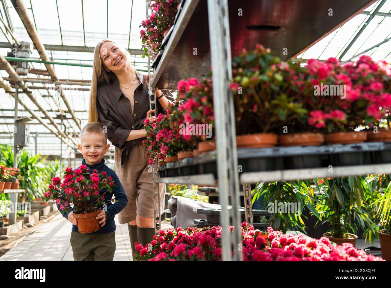 Little boy with a flower in a pot and his mom, a florist who pulls a ...
