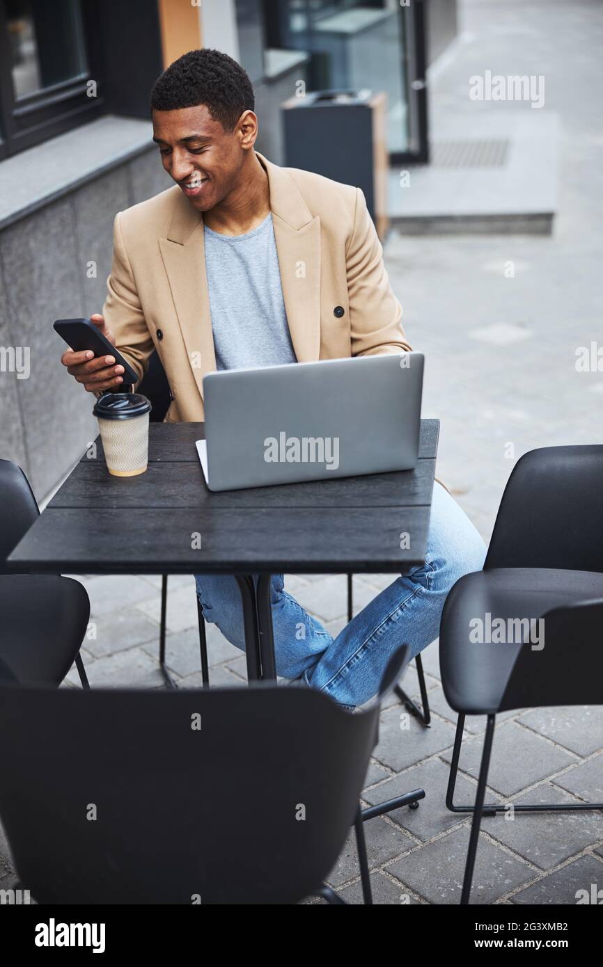 Handsome dark-skinned man reading message on screen Stock Photo - Alamy
