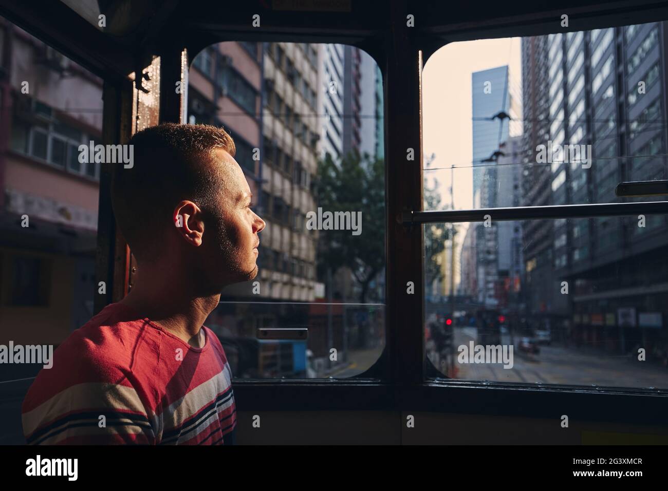 Pensive man looking out old tram window. Tourist exploring city streets ...