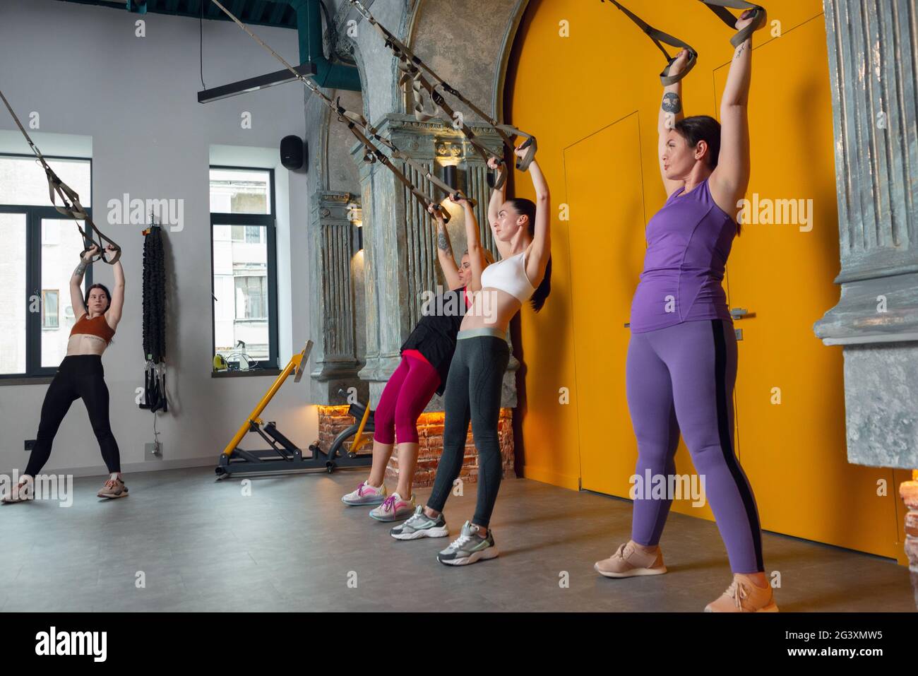 Athletic multinational people doing exercise with elastic rope in gym ...