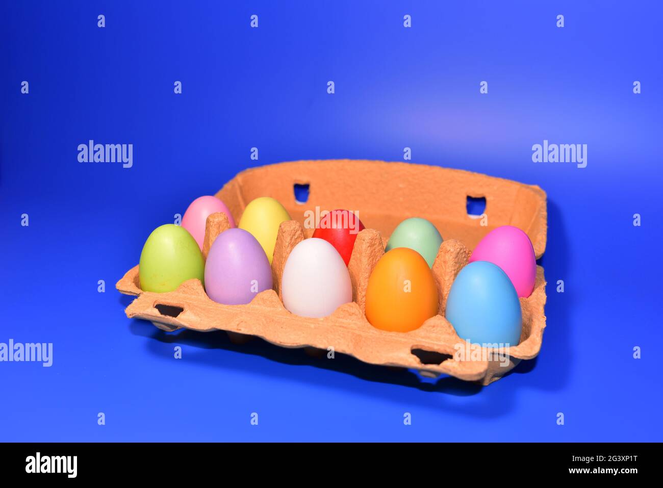 Easter eggs in a paperboard. Multi-colored eggs in egg carton on blue ...