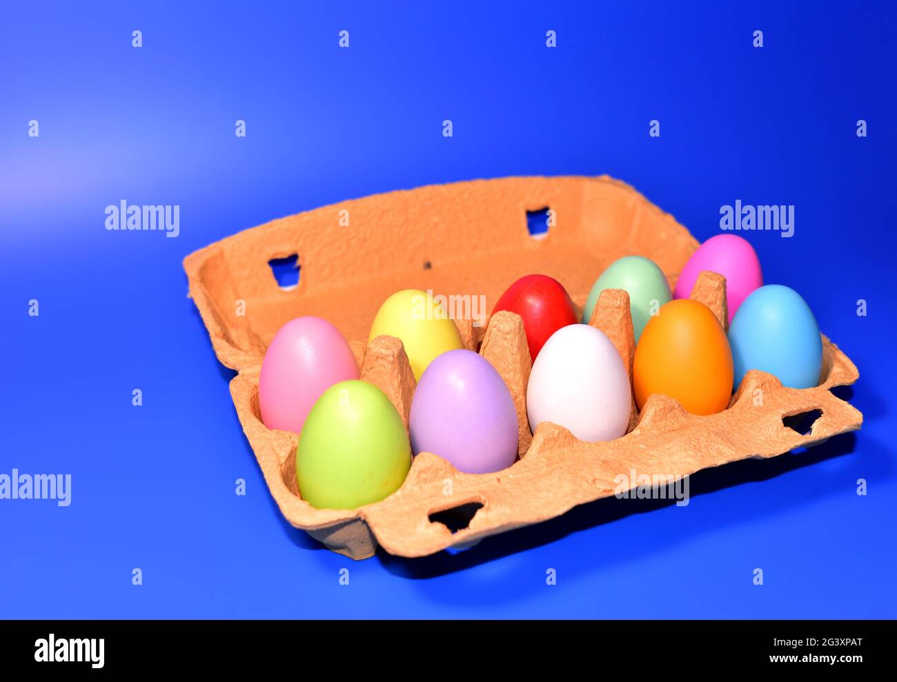 Easter eggs in a paperboard. Multi-colored eggs in egg carton on blue ...