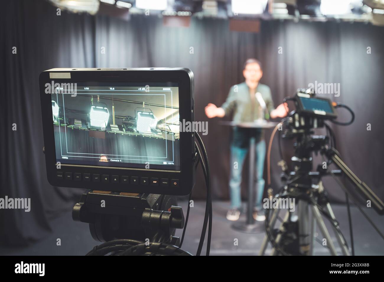 Young journalist in a television recording studio is talking into a ...