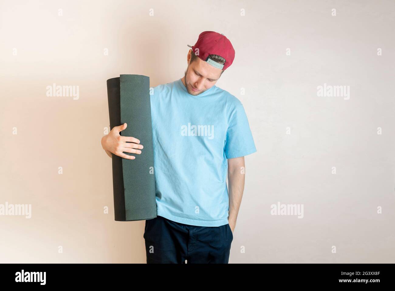 young man holding a yoga mat and carry it to the class, copy space ...