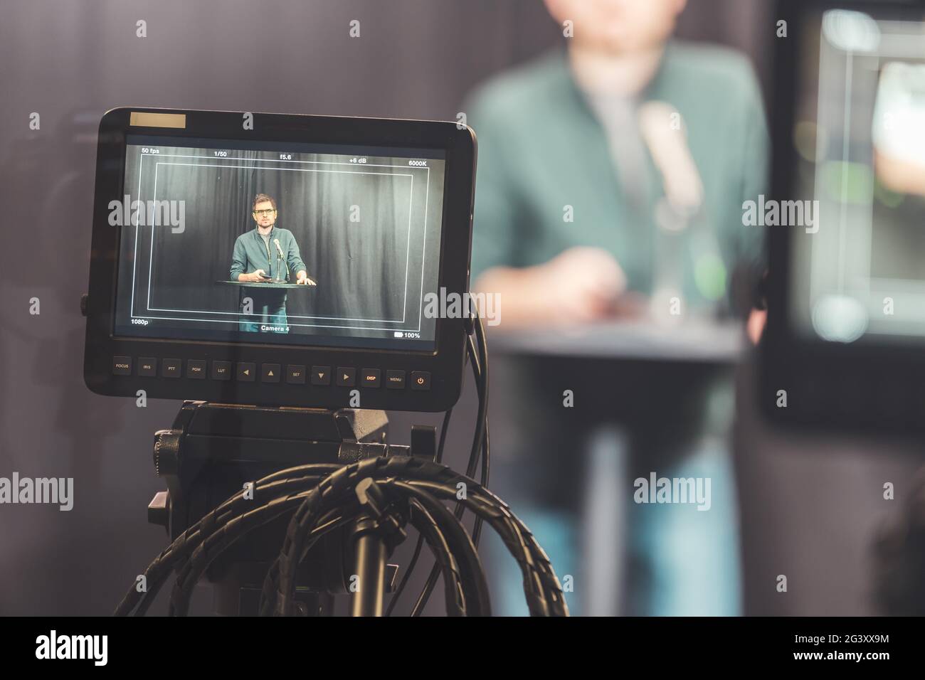 Young journalist in a television recording studio is talking into a ...