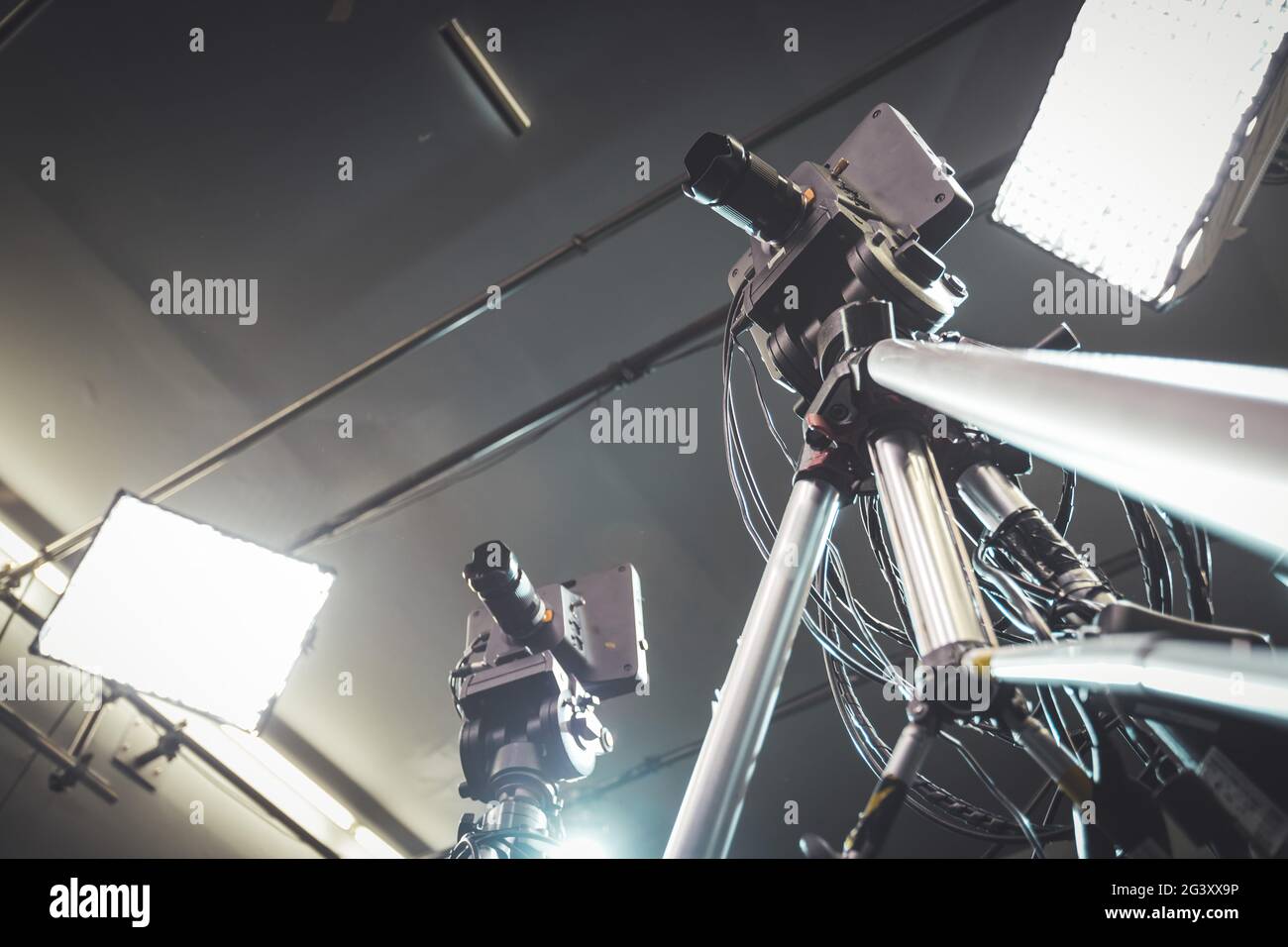 Professional film camera on tripod, broadcasting studio, spotlights and ...