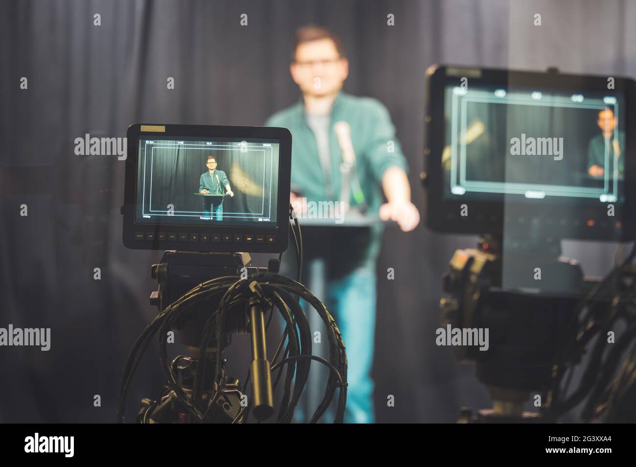 Young journalist in a television recording studio is talking into a ...