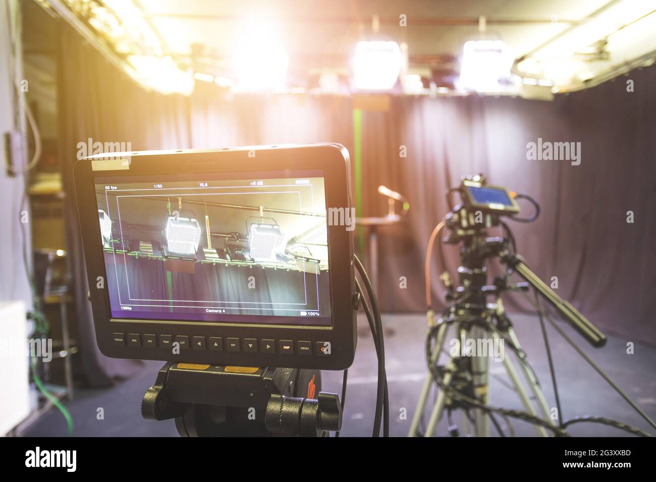 Professional film camera on tripod, broadcasting studio, spotlights and ...