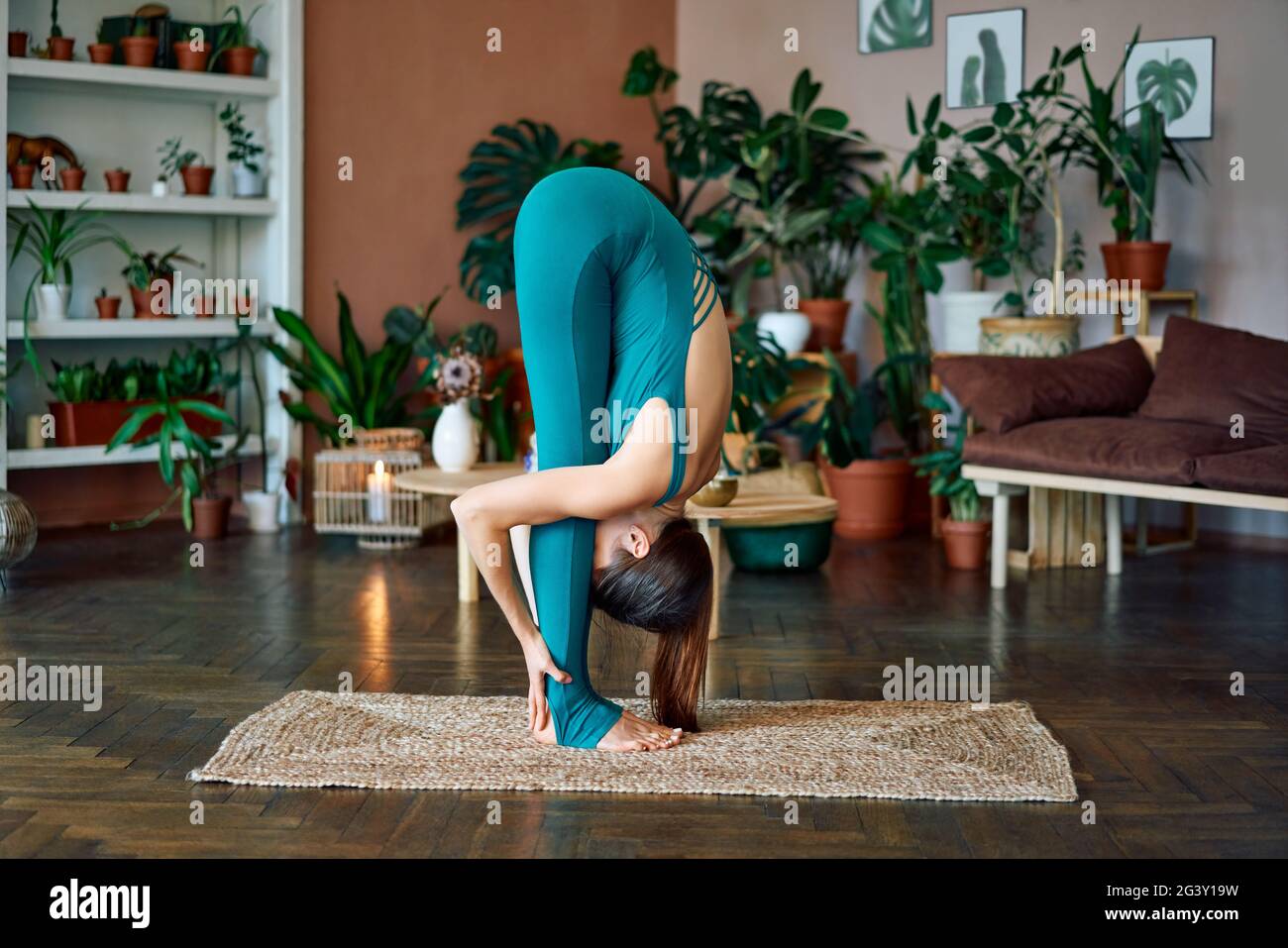 Young slim woman practicing yoga doing standing forward bend pose ...