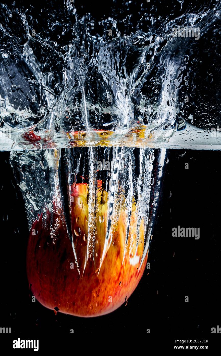 red apple thrown into water with splash and black background Stock ...