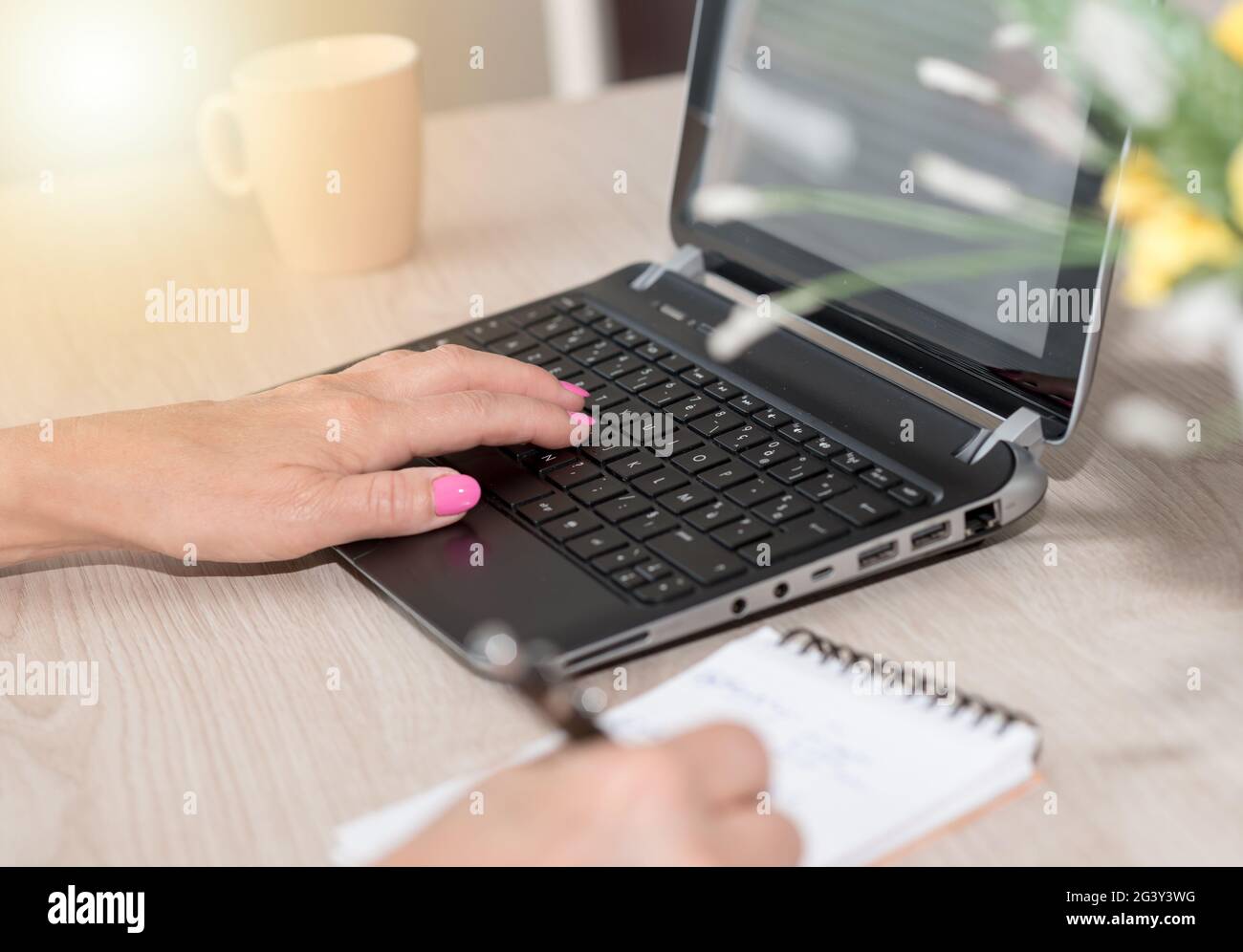Female hands taking notes on a notebook and working on laptop, light ...