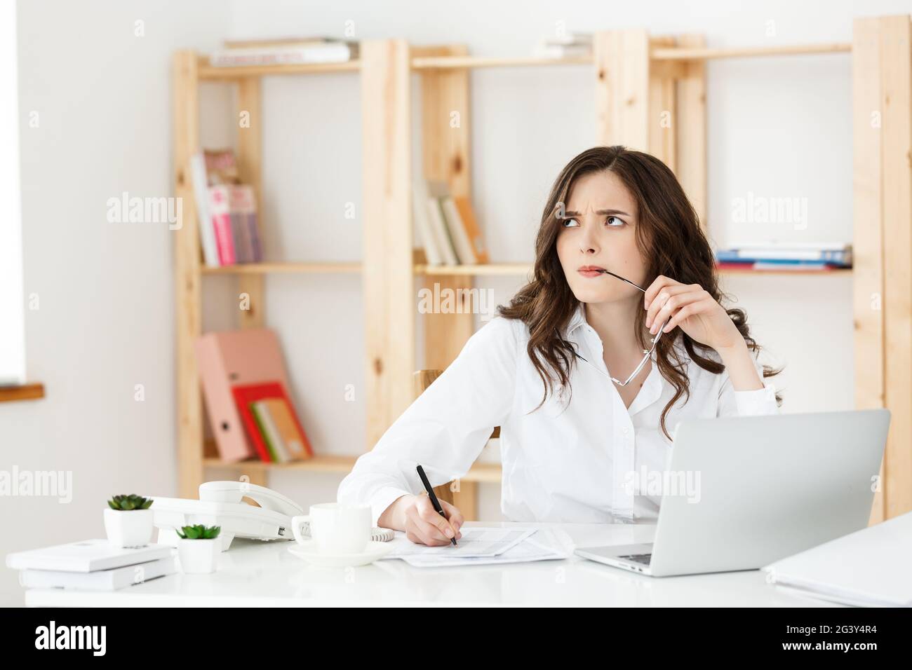 Young attractive woman at a modern office desk, working with laptop and ...