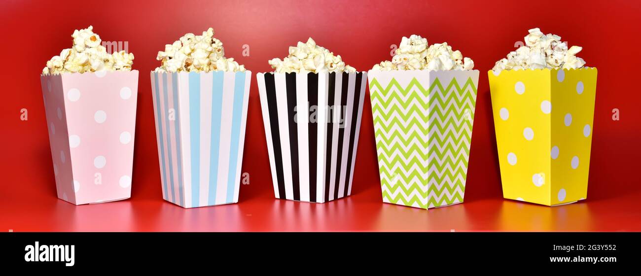 Popcorn in colored cardboard packaging. Heap of salted popcorn in paper ...