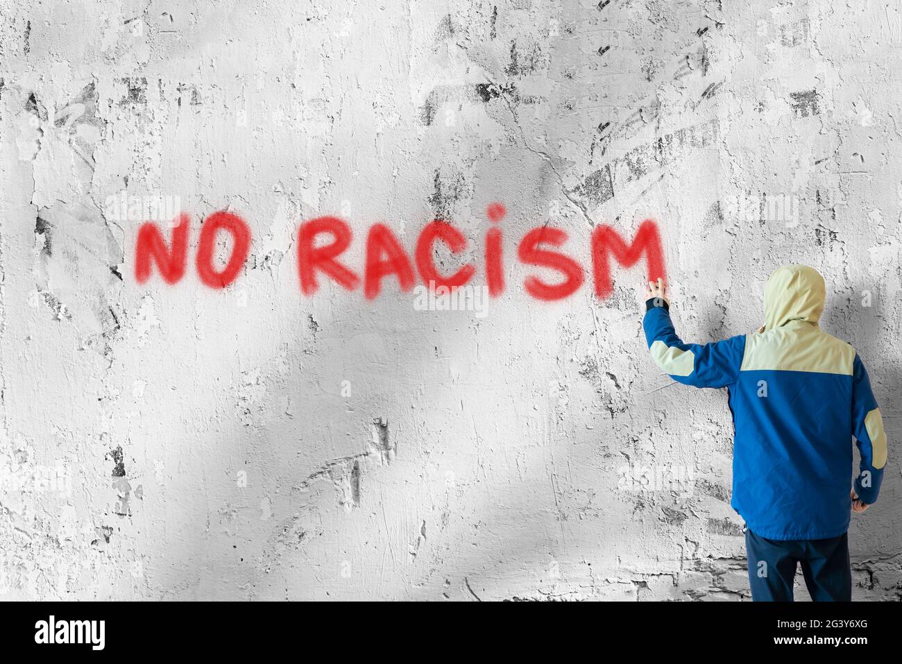 person male write with spray paint can the stop no racism statement on ...