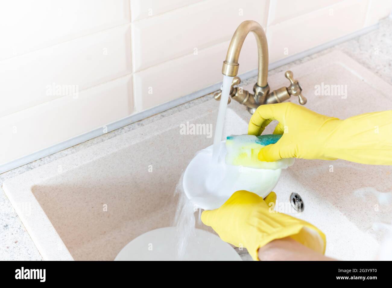 hands holding dirty dish and wash it in the kitchen sink pouring water ...