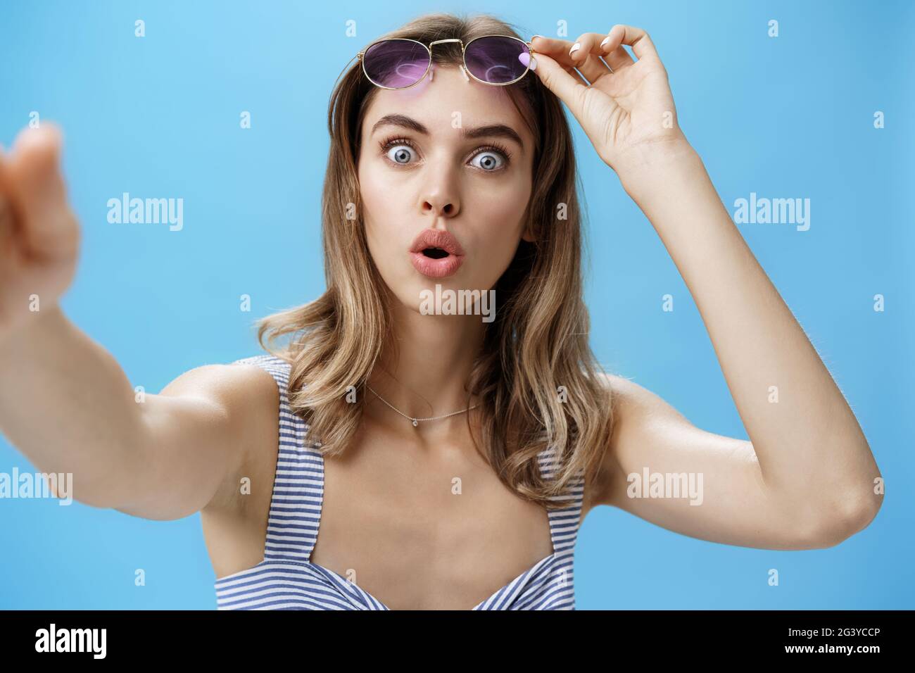 Woman taking off glasses while looking at herself in frontal camera of ...
