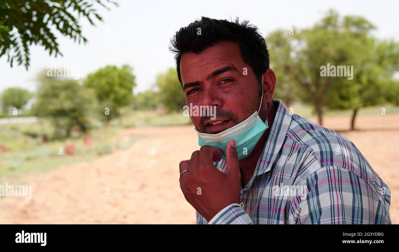 Handsome Indian man wearing mask and check shirt over blur background ...