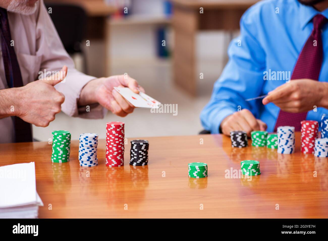 Two male employees playing cards at workplace Stock Photo - Alamy