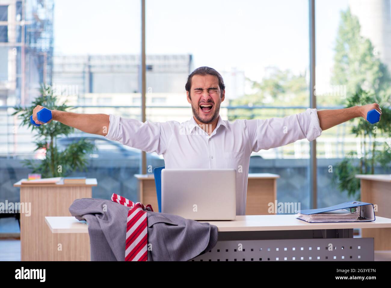 Young male employee doing sport exercises in the office Stock Photo - Alamy