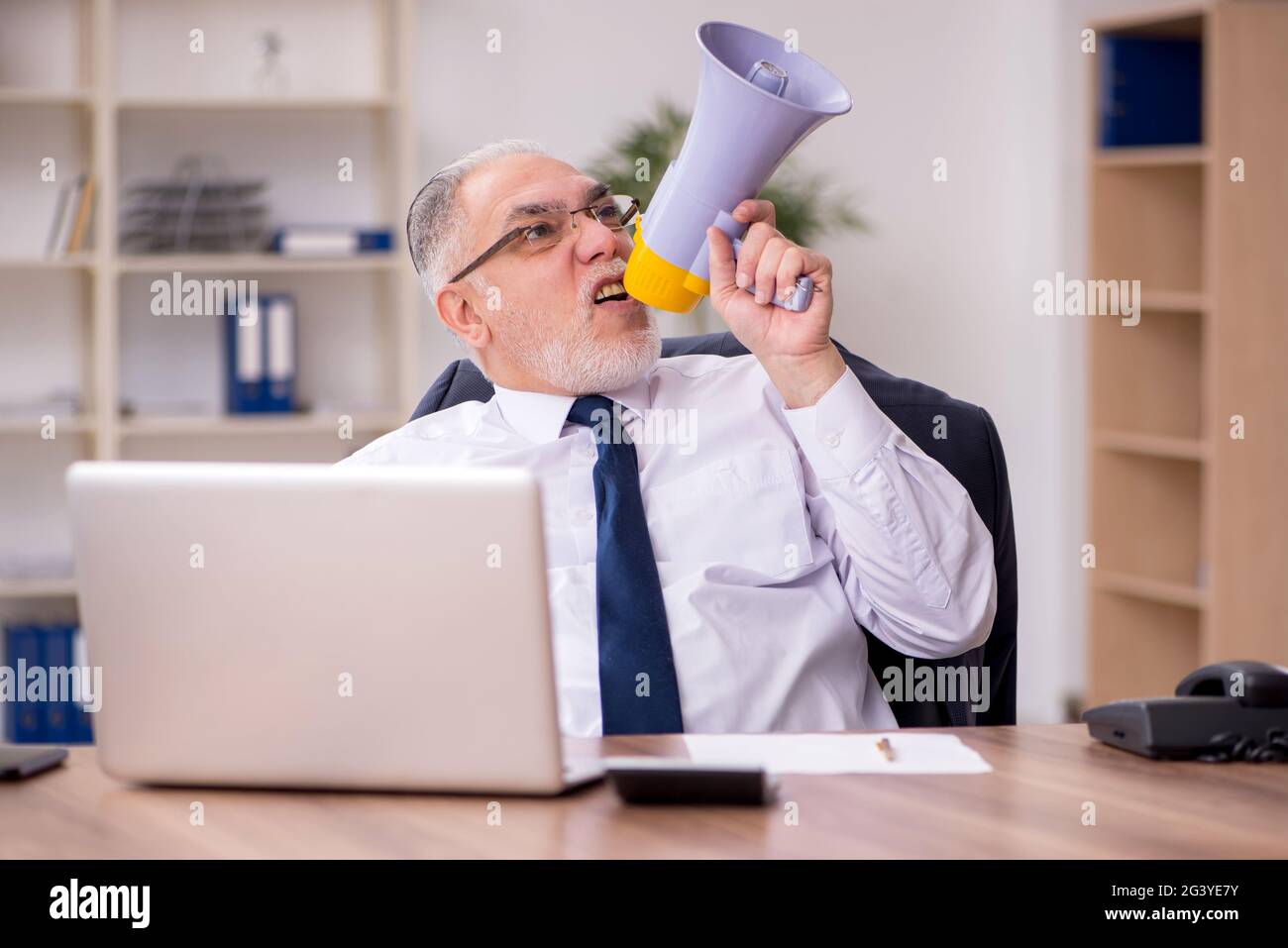 Old male employee holding megaphone at workplace Stock Photo - Alamy