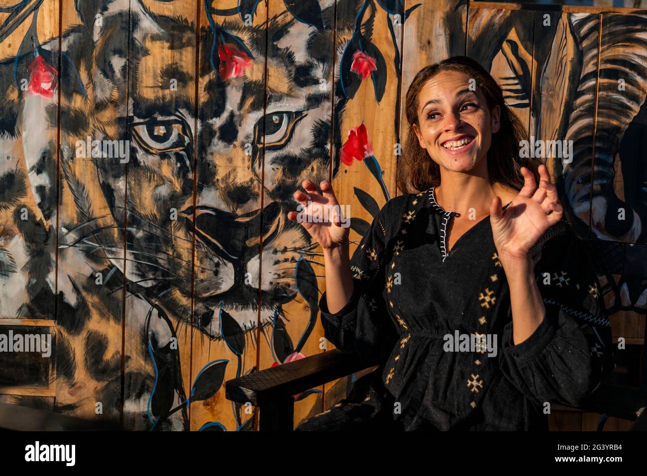 Young woman poses as a wild big cat in front of mural with safari ...