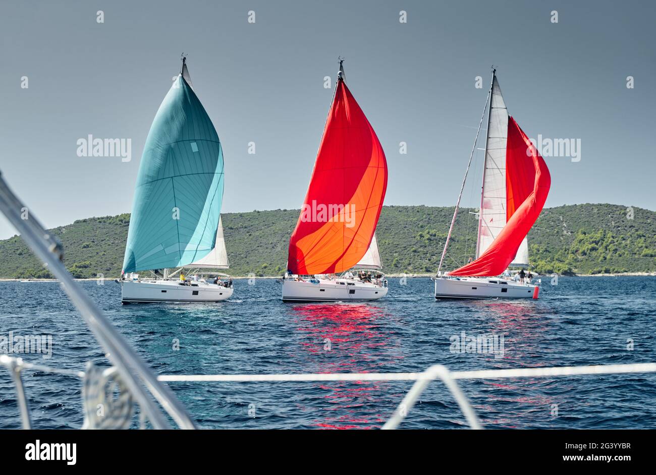 Sailboats compete in a sail regatta at sunset, view throug the ropes ...