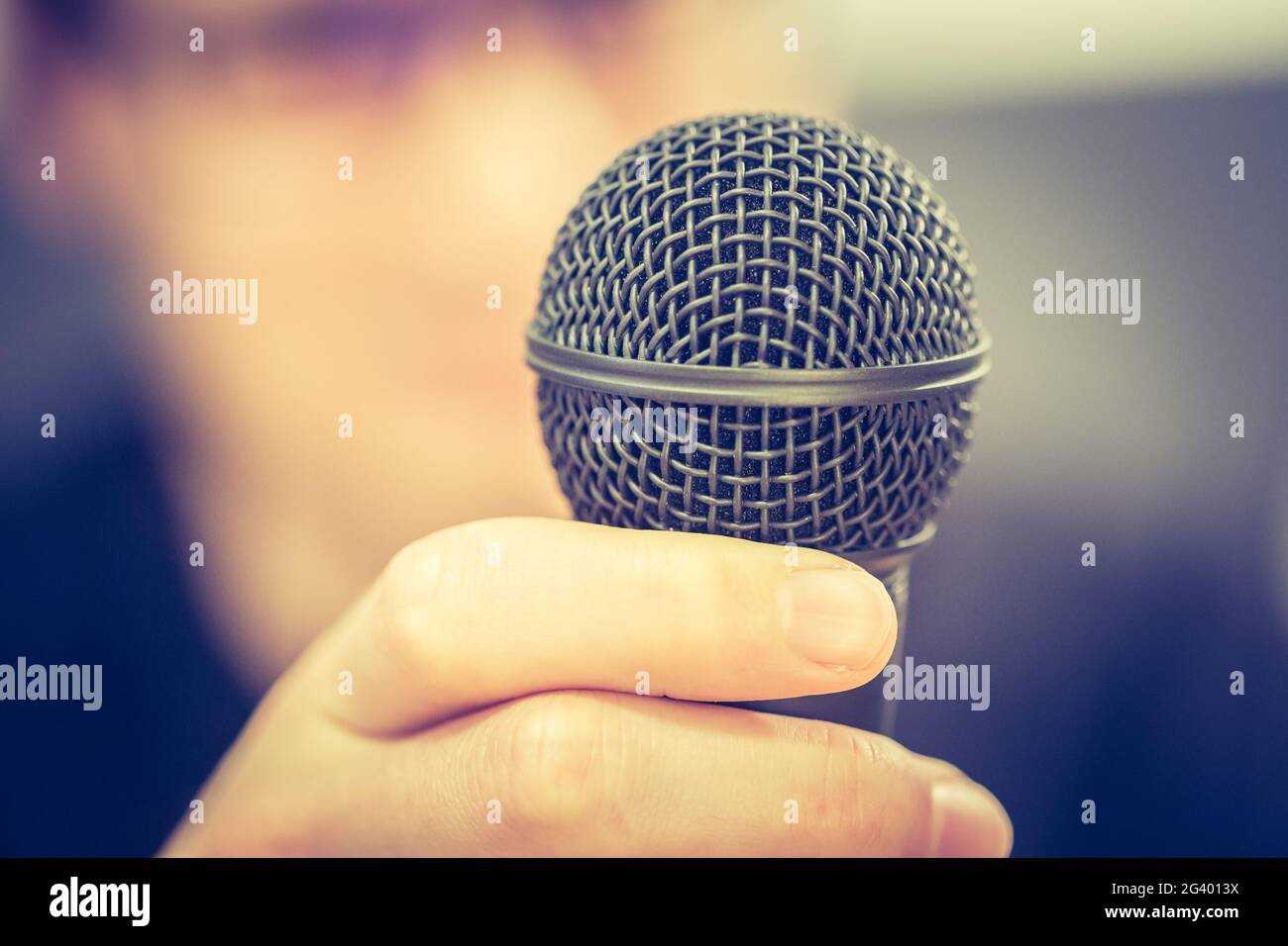 Speaking in the microphone: Young man with blurry face is taking into ...
