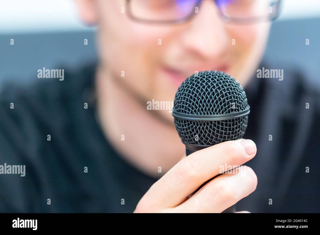 Speaking in the microphone: Young man with blurry face is taking into ...