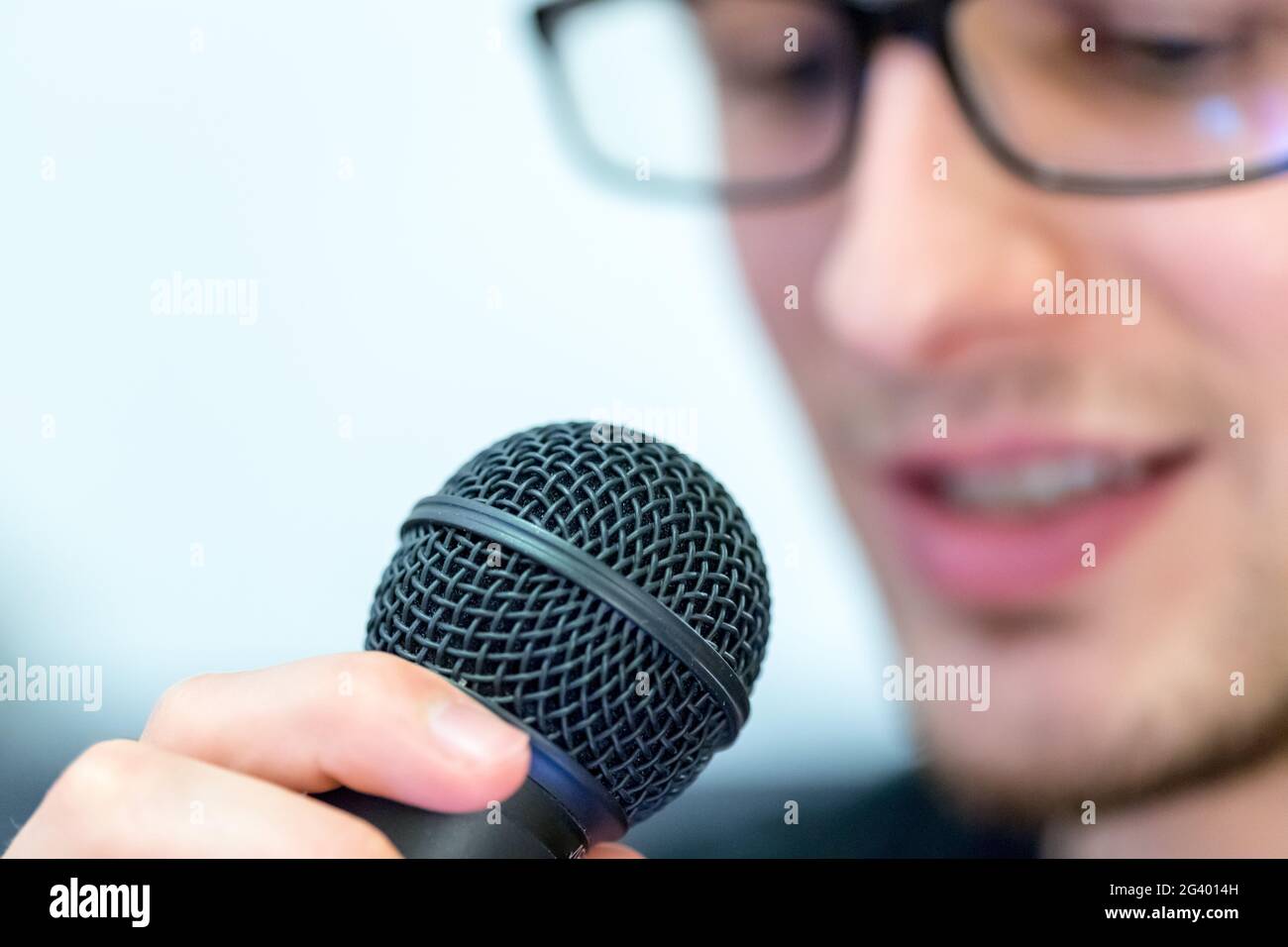Speaking in the microphone: Young man with blurry face is taking into ...