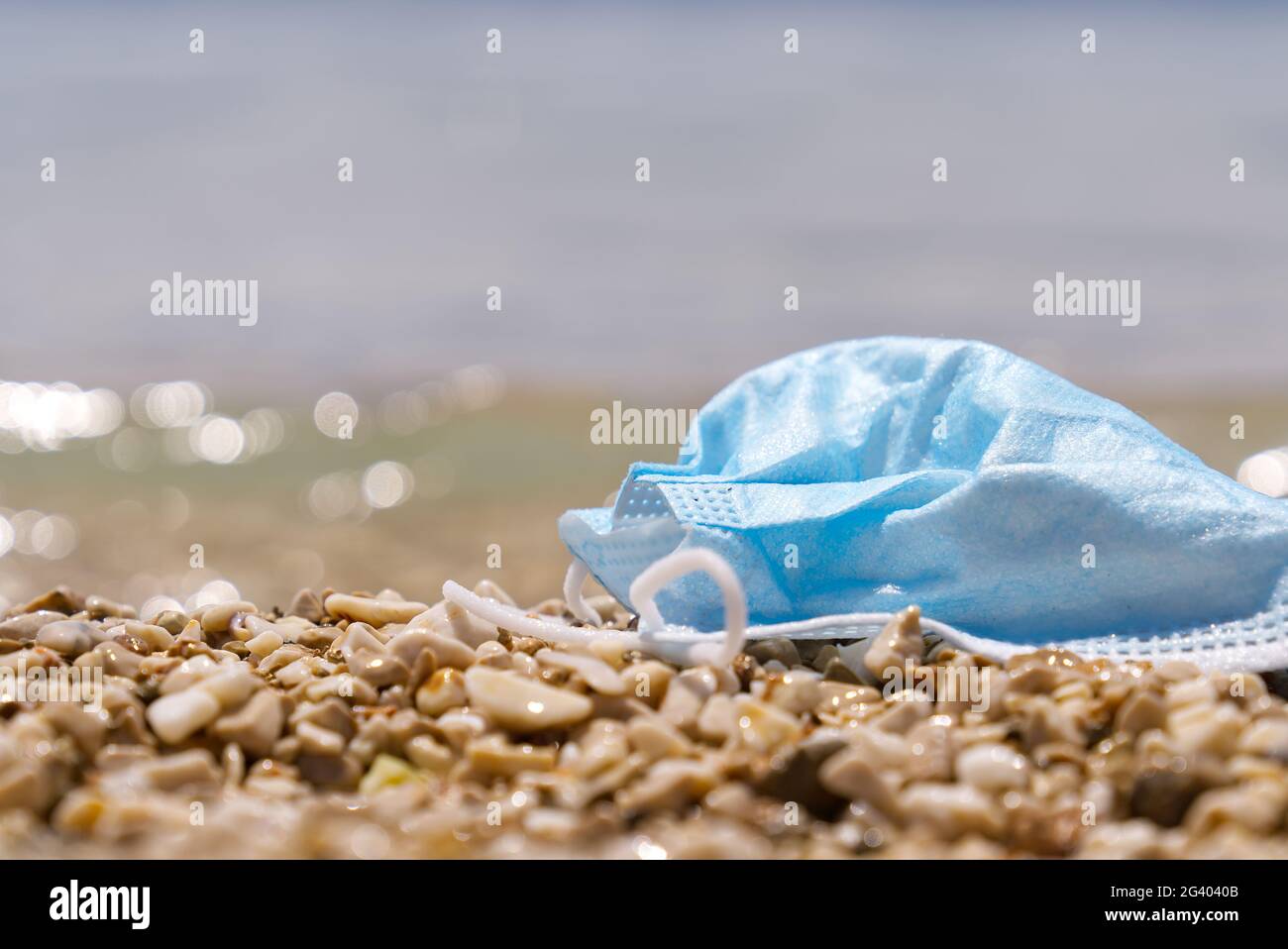 Used blue medical face mask lies on the beach. Environmental and coast ...