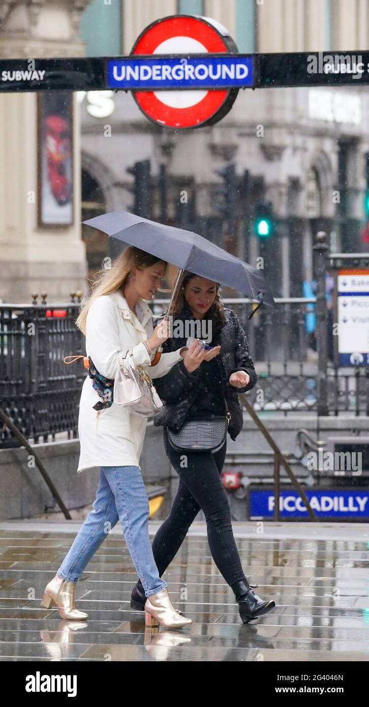 Friends share hand gel as they walk past the entrance to Piccadilly ...