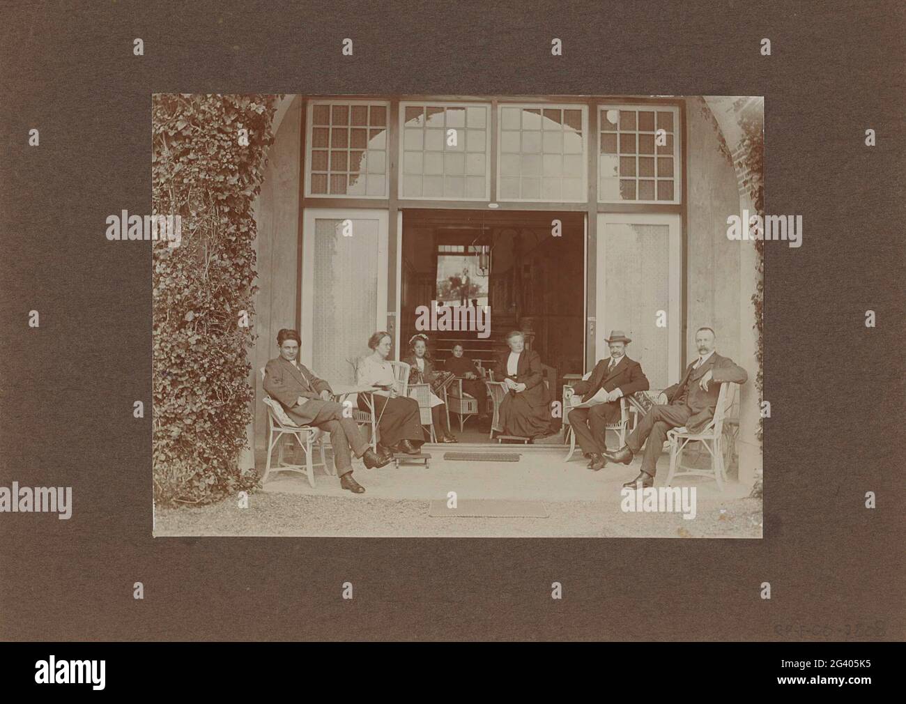 Men, women and children posing at a veranda, in the background the ...