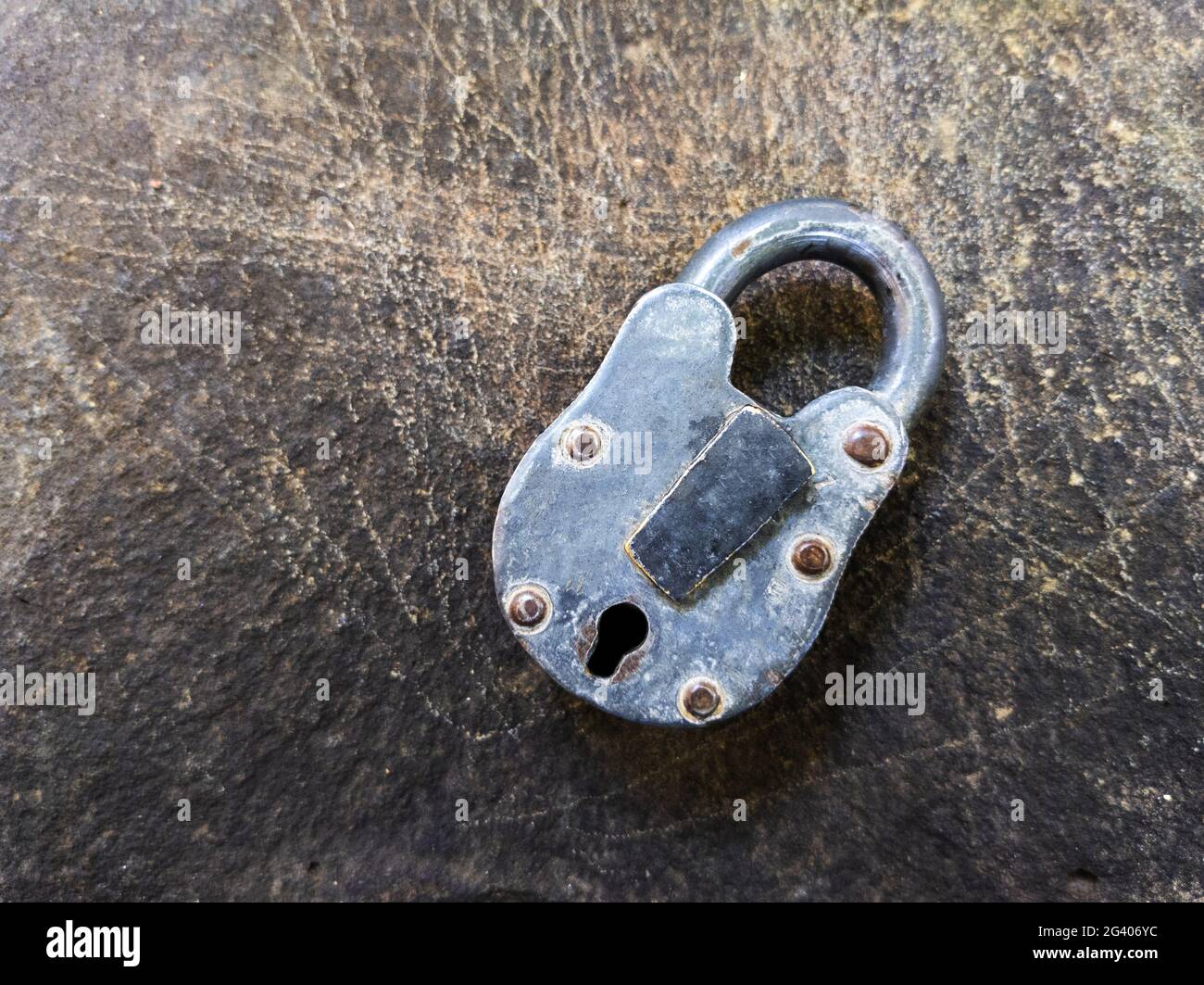 Closeup of an old padlock on a rough metal surface with scratch marks ...
