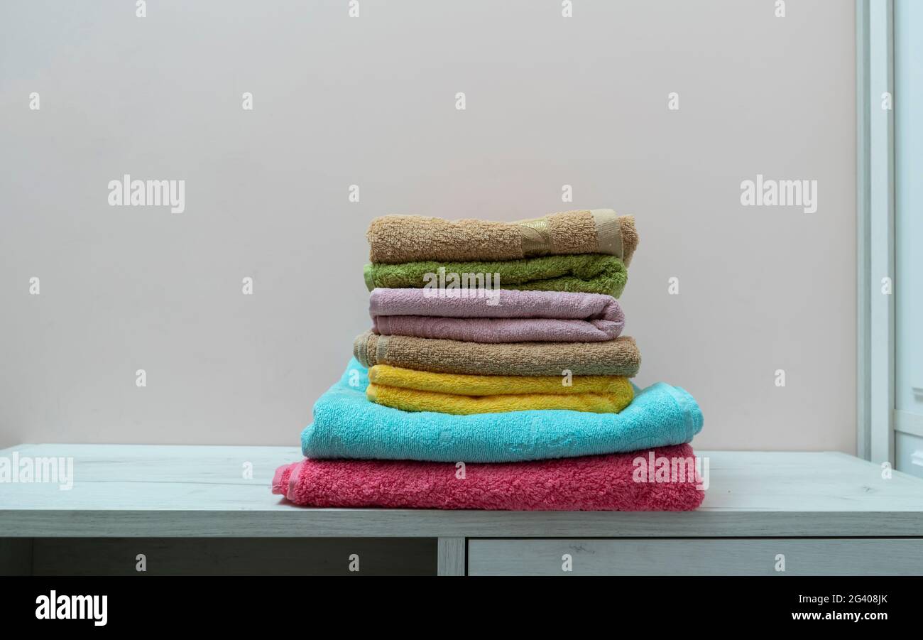 stack of new clean fresh color towels textile on the shelf in laundry ...