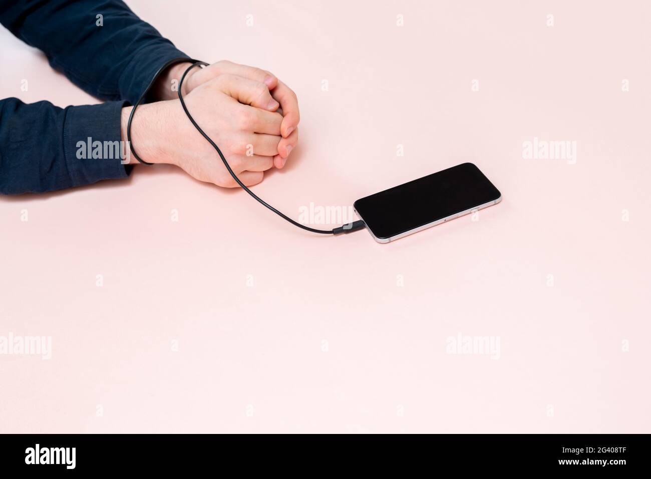 person hands addicted to the digital mobile phone device, wire tied to ...