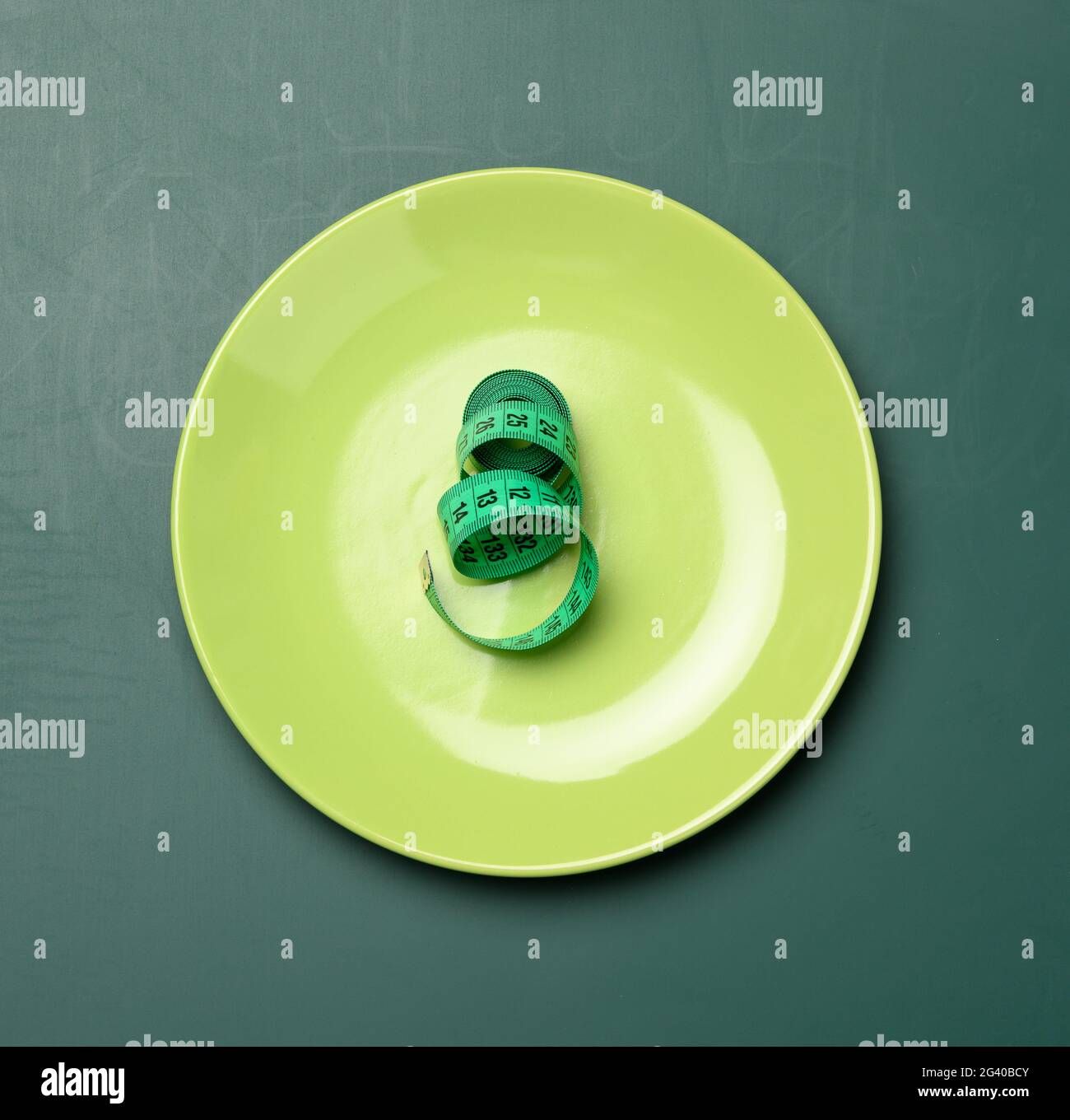 Green round plate and green measuring tape on a green background Stock ...