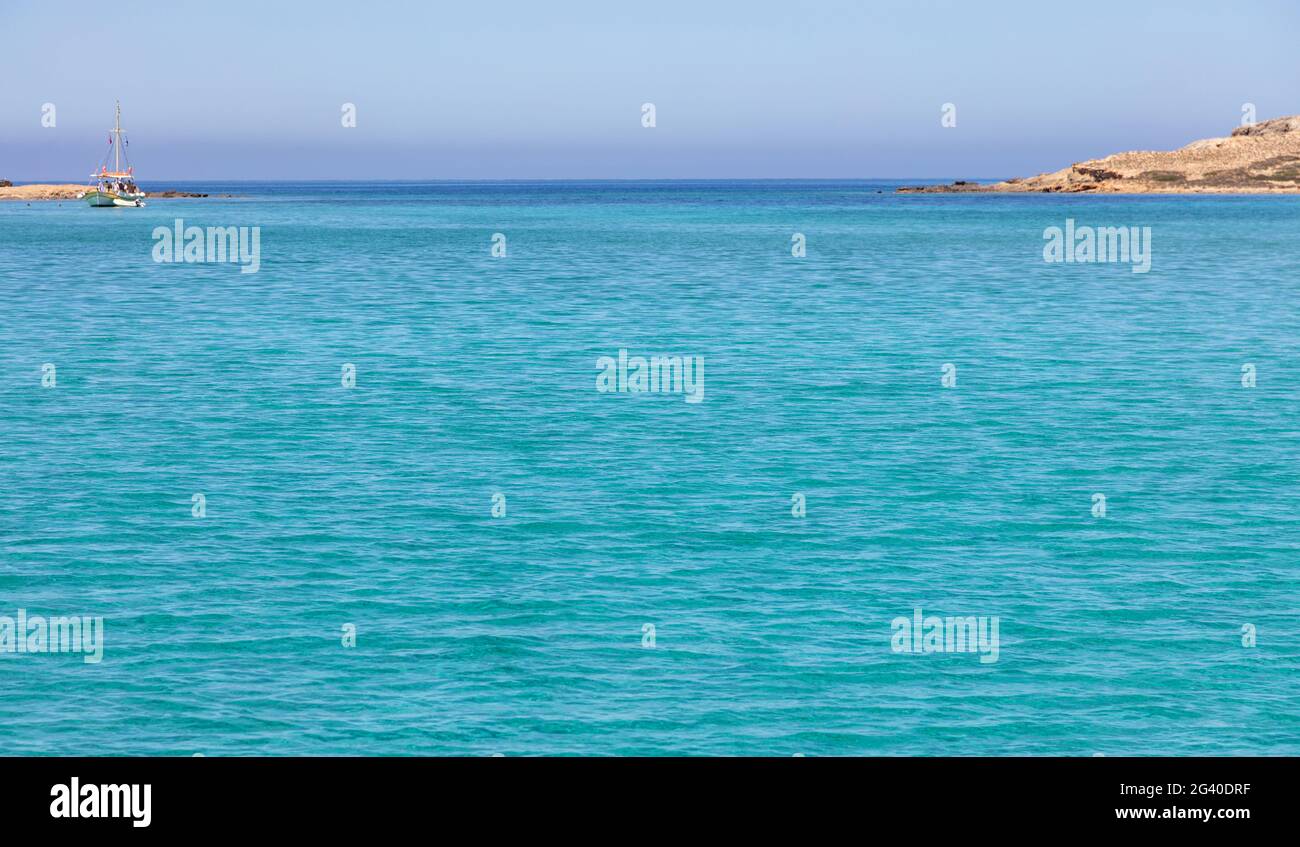 Sailboat anchored on turquoise blue sea, island coast and blue sky ...