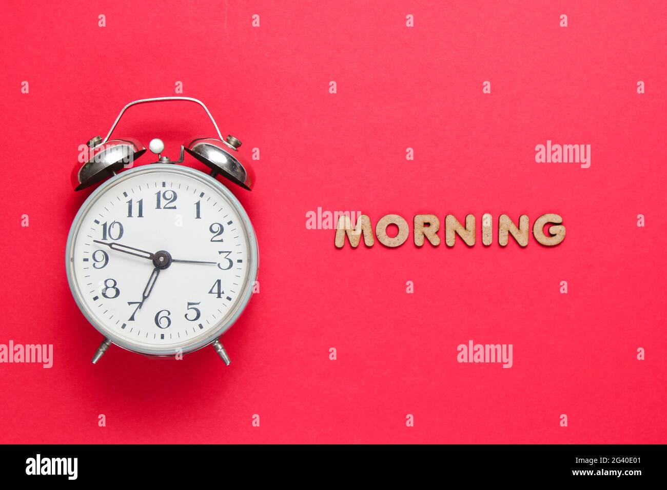 Retro alarm clock on red background with text morning with letters ...