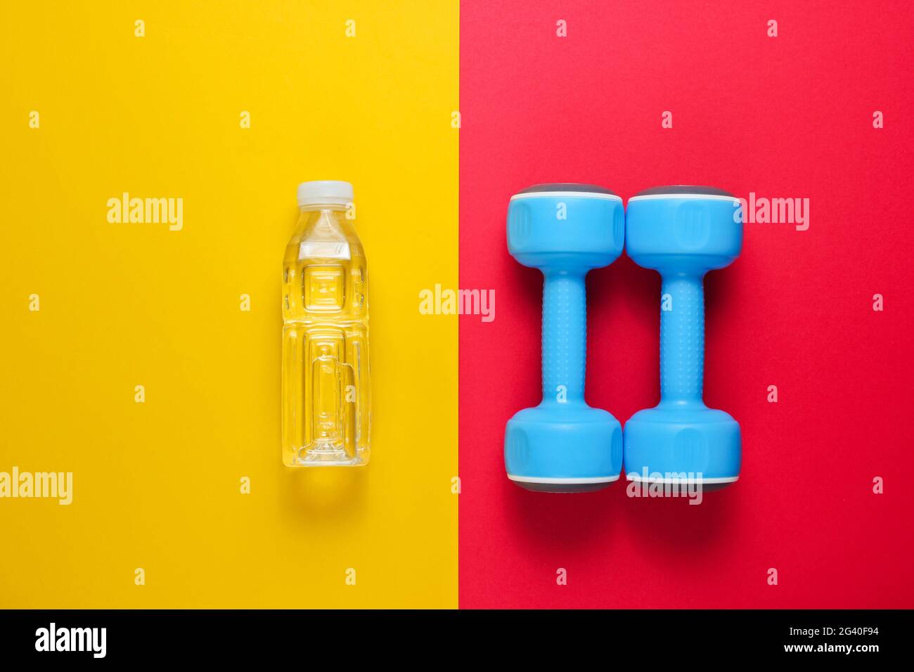 Minimalistic fitness concept. Dumbbells, bottle of water on colored ...