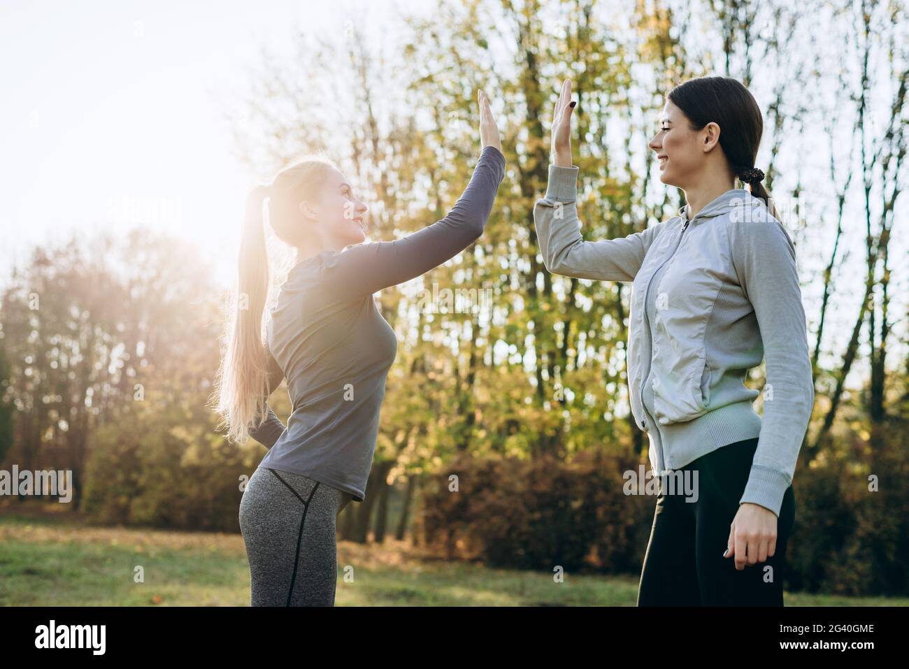 Young girls giving high five to one another while workout outdoors ...