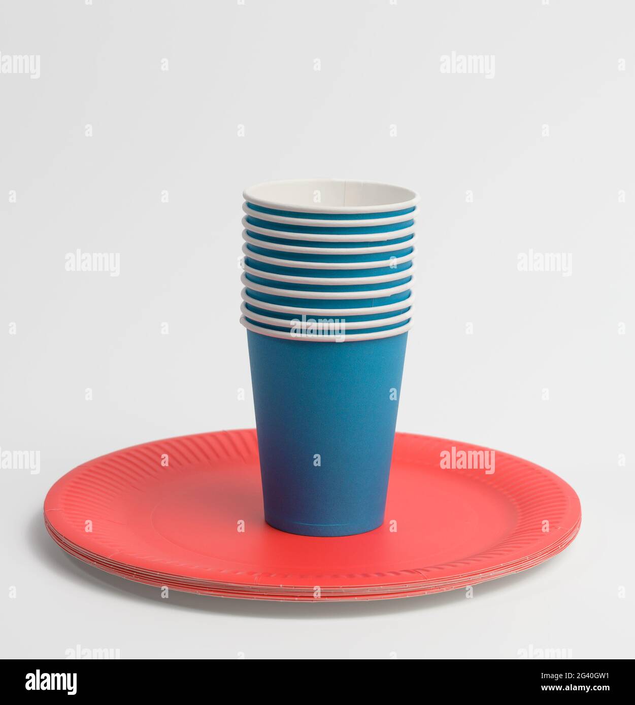 Stack of blue paper cups and red round plates on a white background ...