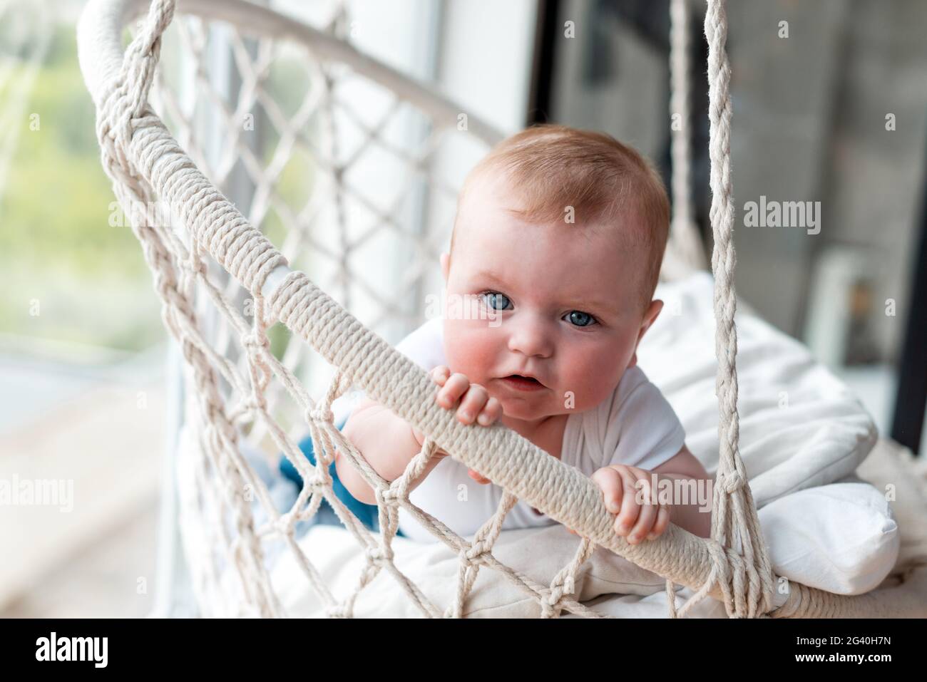 A little girl sitting in a hanging chair in the bedroom Stock Photo - Alamy