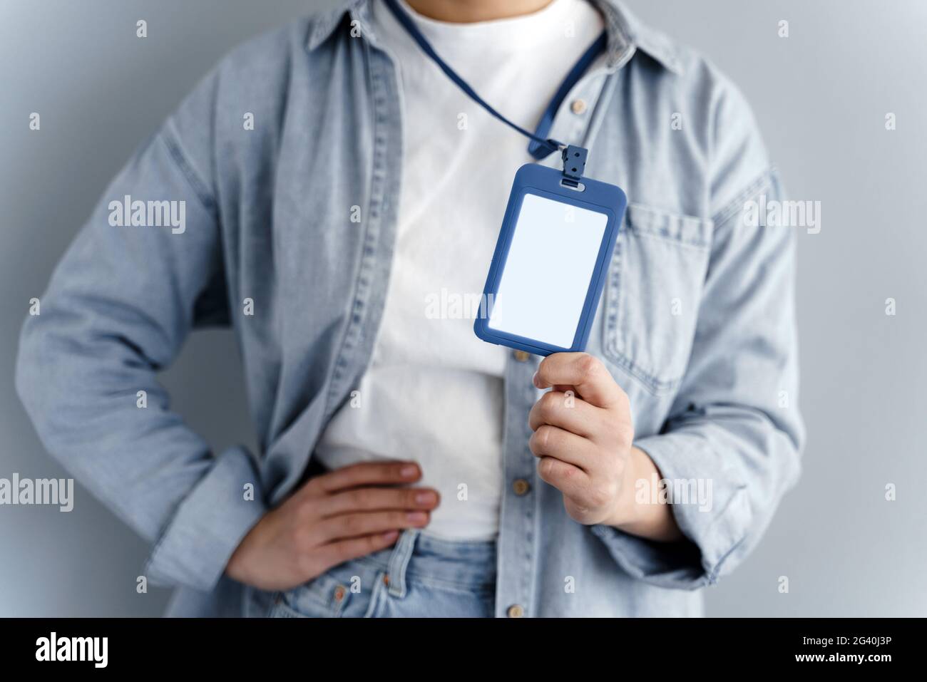 Young caucasian girl showing name tag on gray background. Close view ...