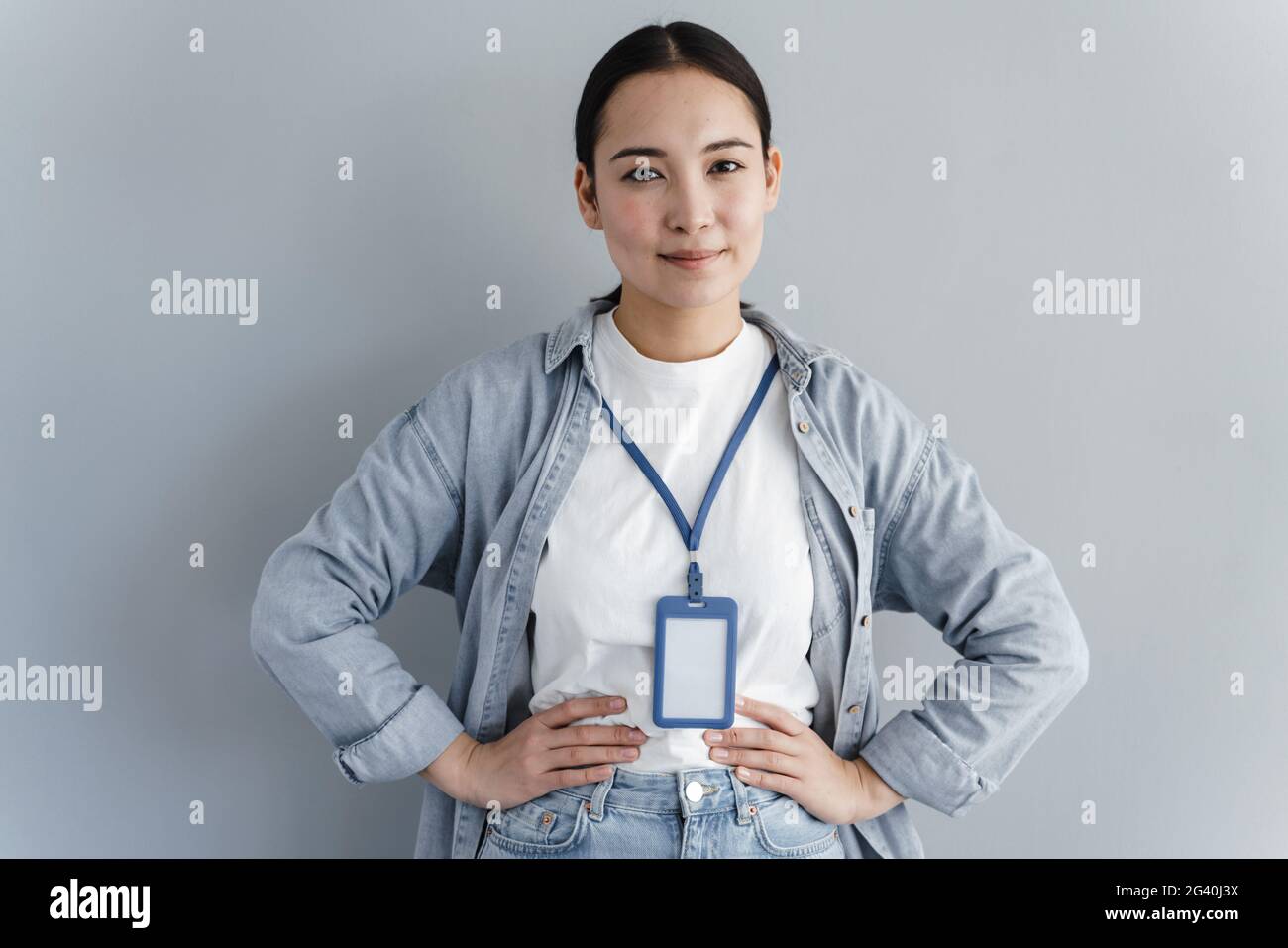 Pretty woman with name tag on gray background. Close view, blank name ...