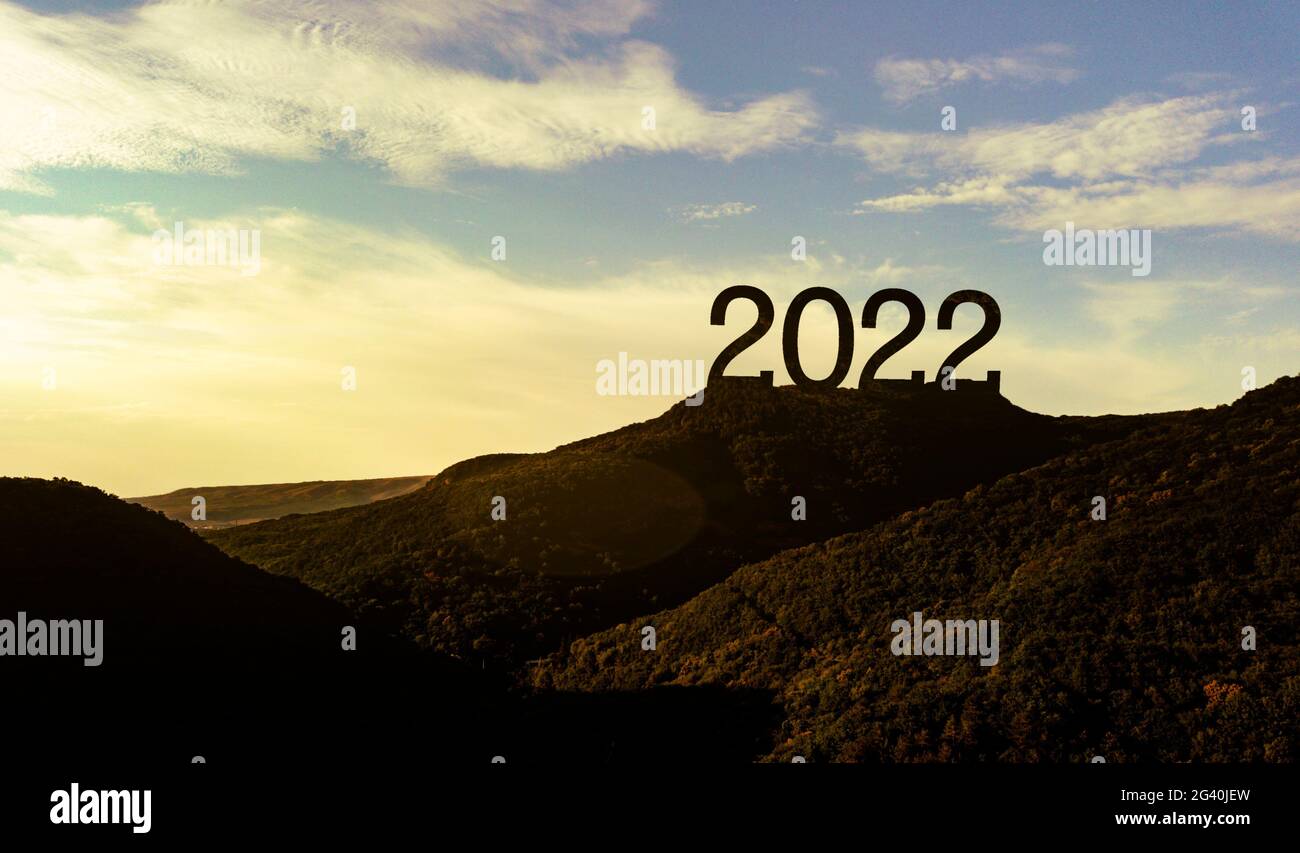 2022 happy new year sign on top of the mountain with sunset, symbol of ...