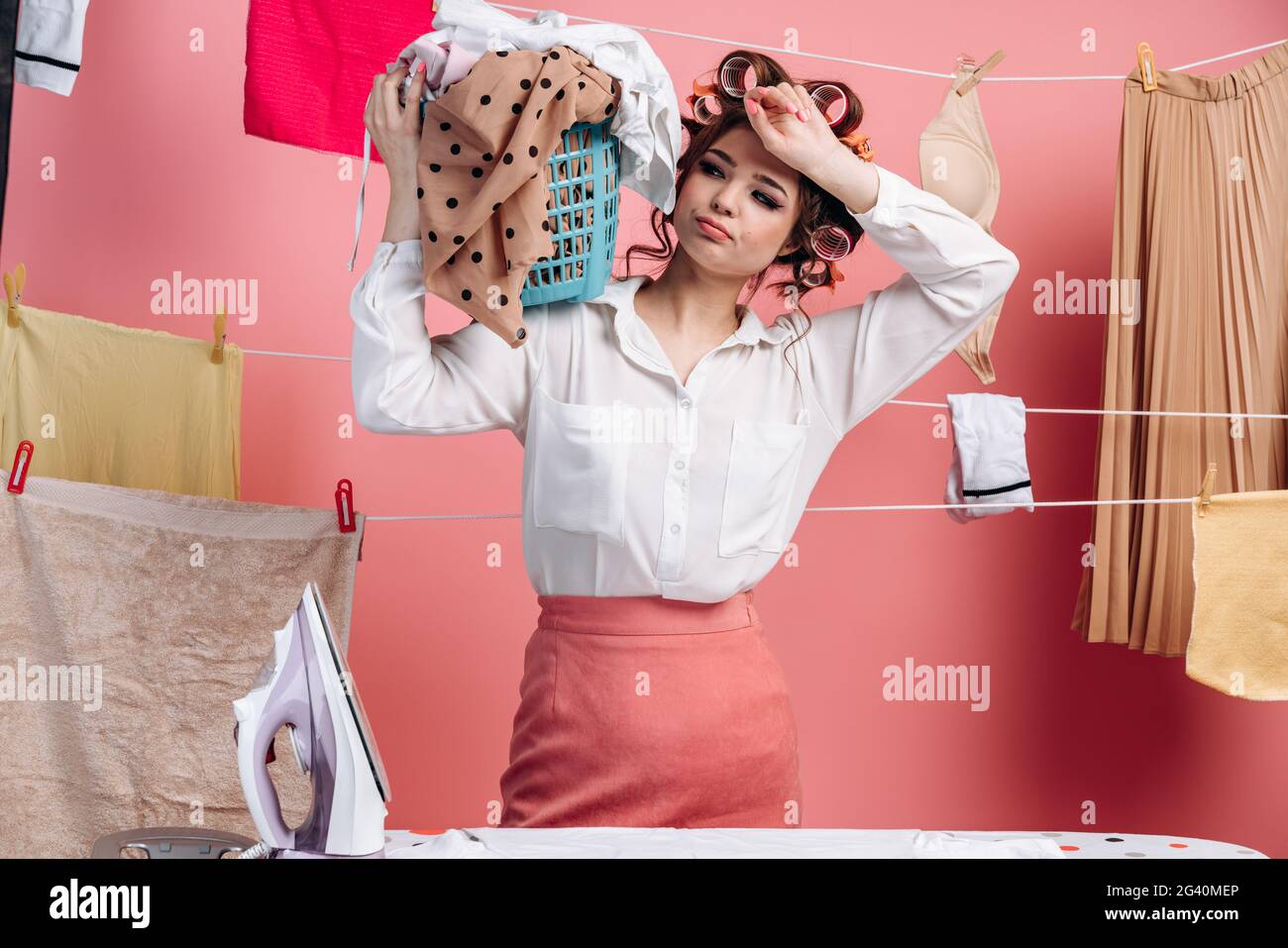 Housewife holds basin with dirty laundry, hangs wet clothes on clothes ...